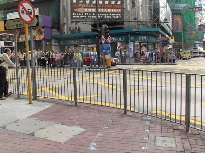 4 photos show an intersection with a railing extending along the curb ...